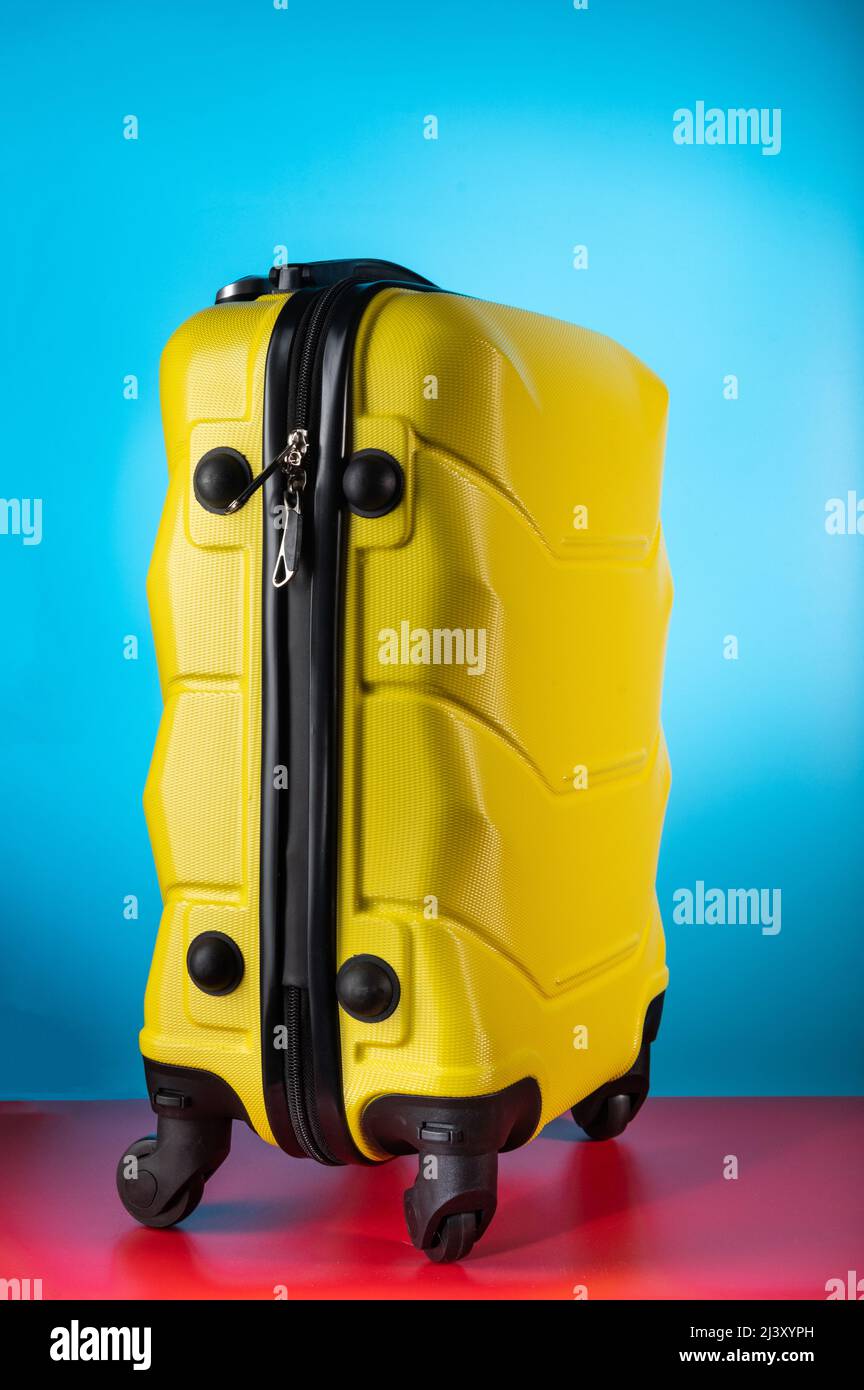 Yellow travel suitcase on wheels on a blue background.Suitcase side ...