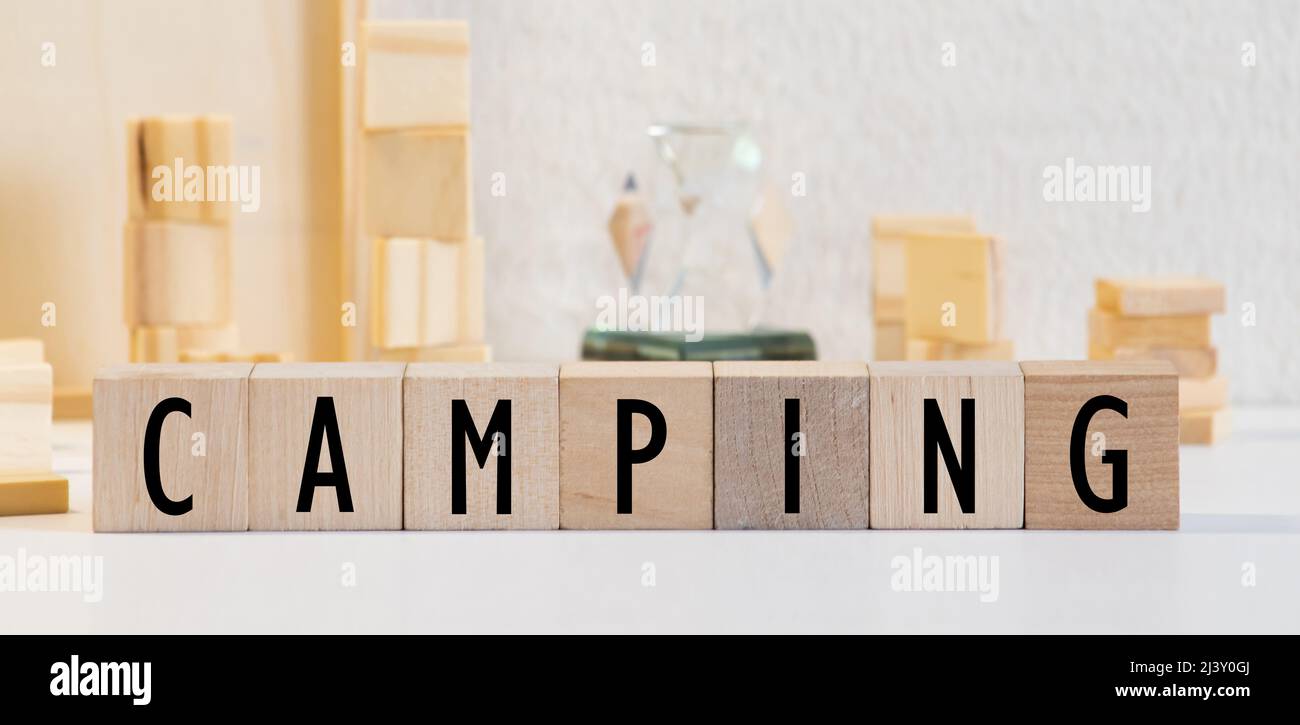 Camping word on a wooden cube sign with a blurry background of a ...