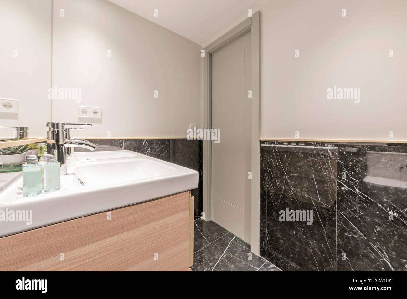 Bathroom with wooden furniture, porcelain sink and frameless mirror ...