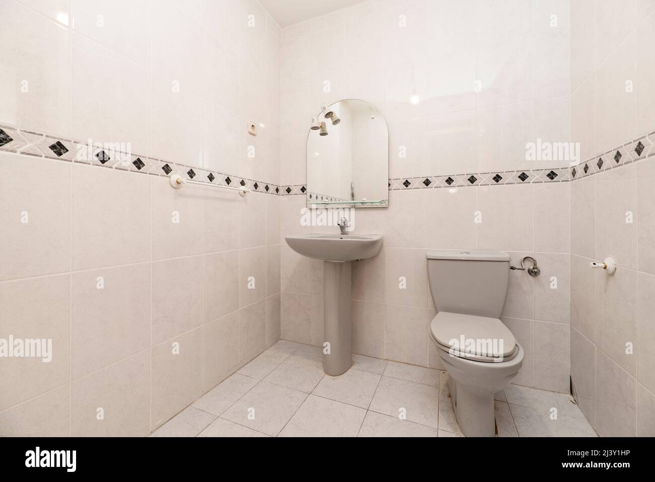 Bathroom with a frameless mirror, a border on the wall tiles and gray ...