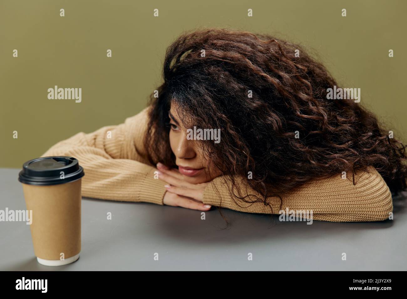 Enjoyed smiling happy tanned curly Latin female look at coffee cup to ...