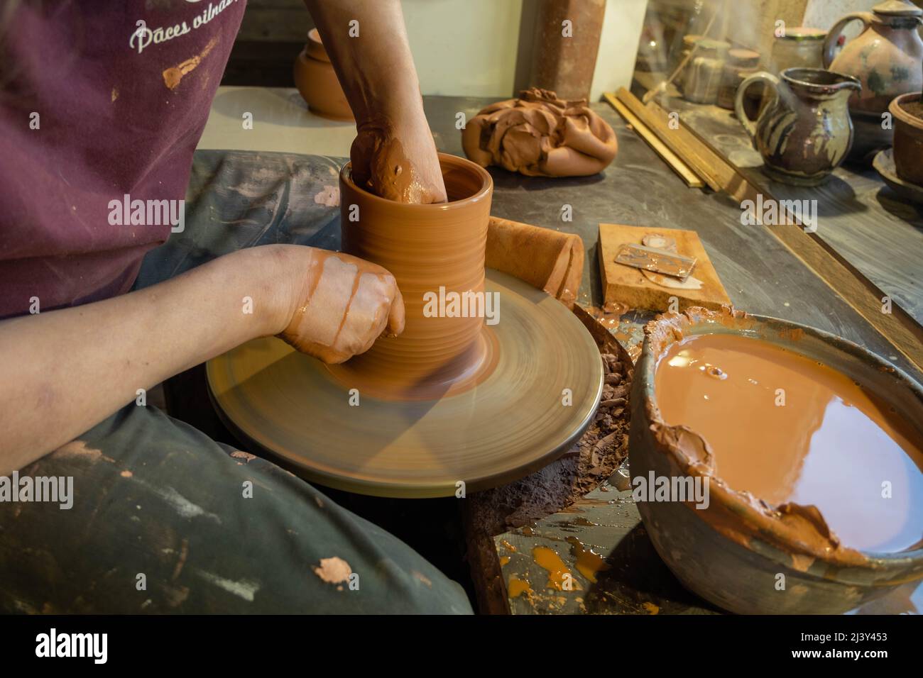 A master potter in an old craft workshop professionally forms a pot of ...