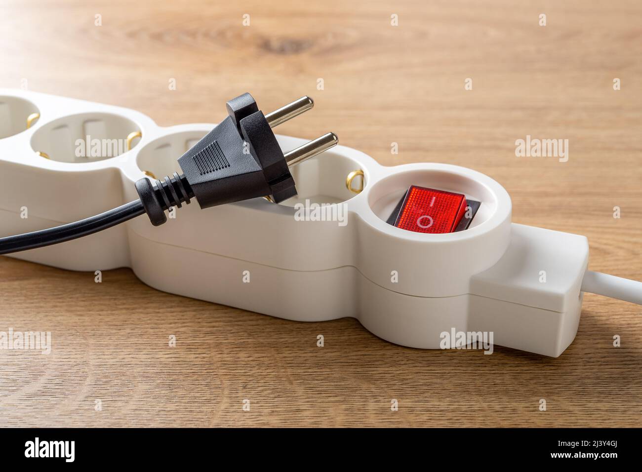 Unplugged electric appliance plug over switched off white power strip ...
