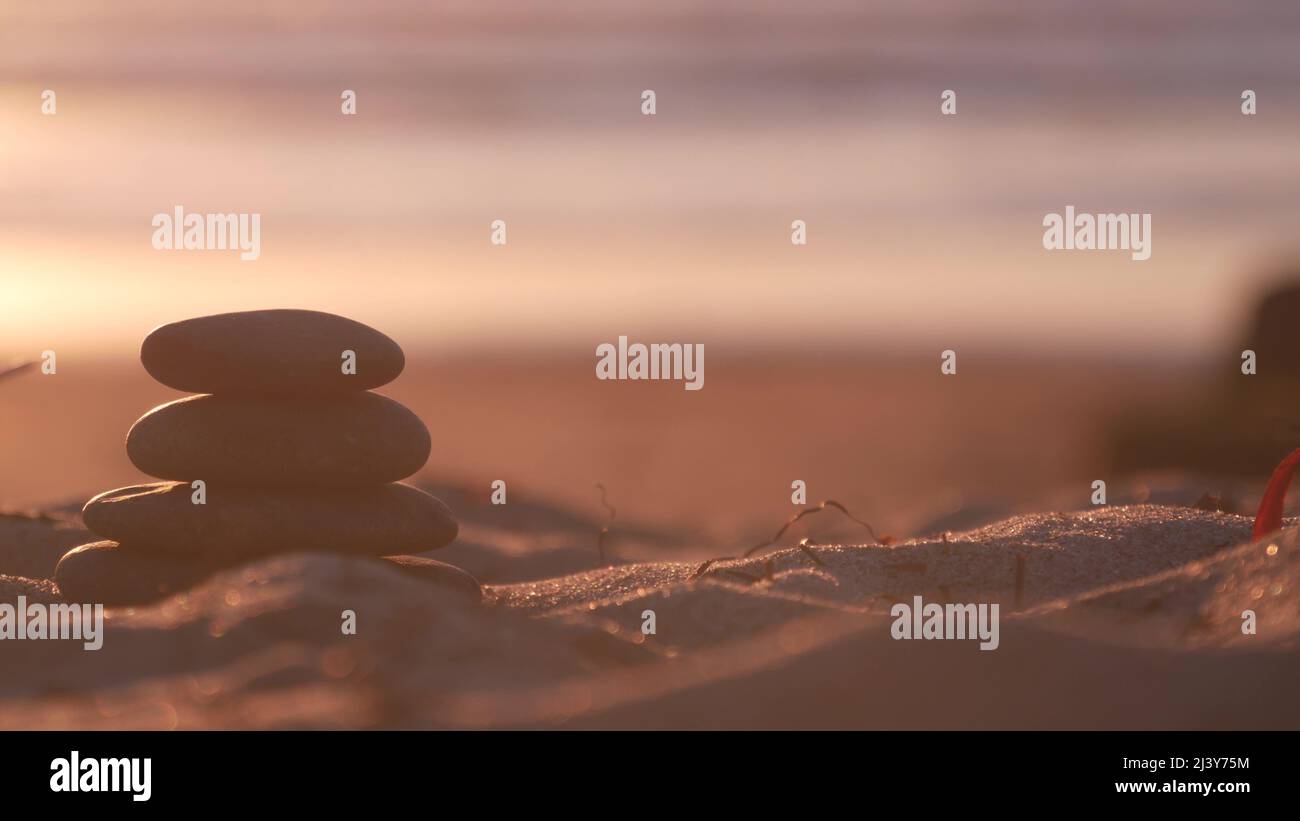 Stack of pebble stones, sandy ocean beach, sunset sky. Rock balancing ...