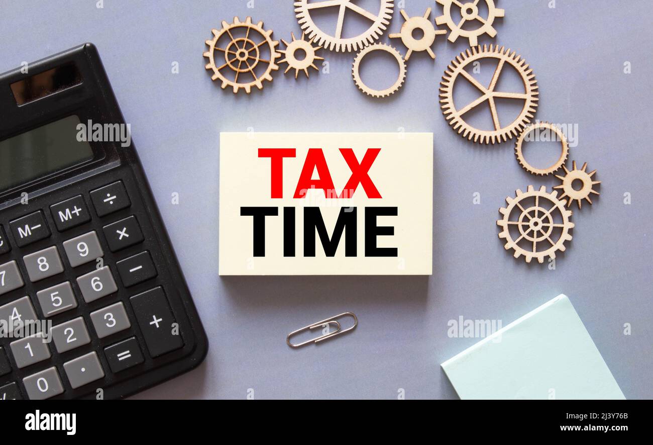 Tax Time written on yellow sticky note pinned with red push pin on cork ...