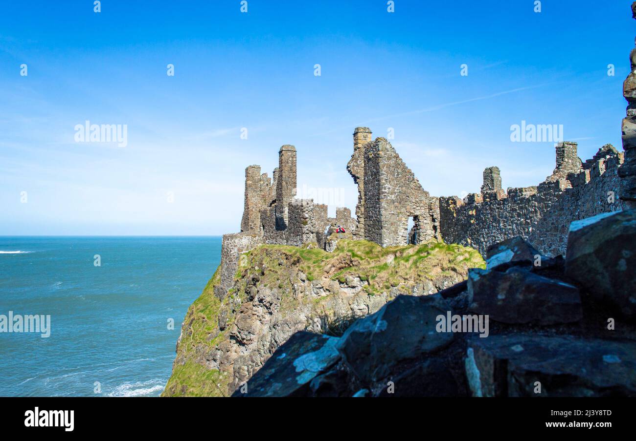 Famous Dunluce Castle on the cliff with blue sea background in a sunny ...