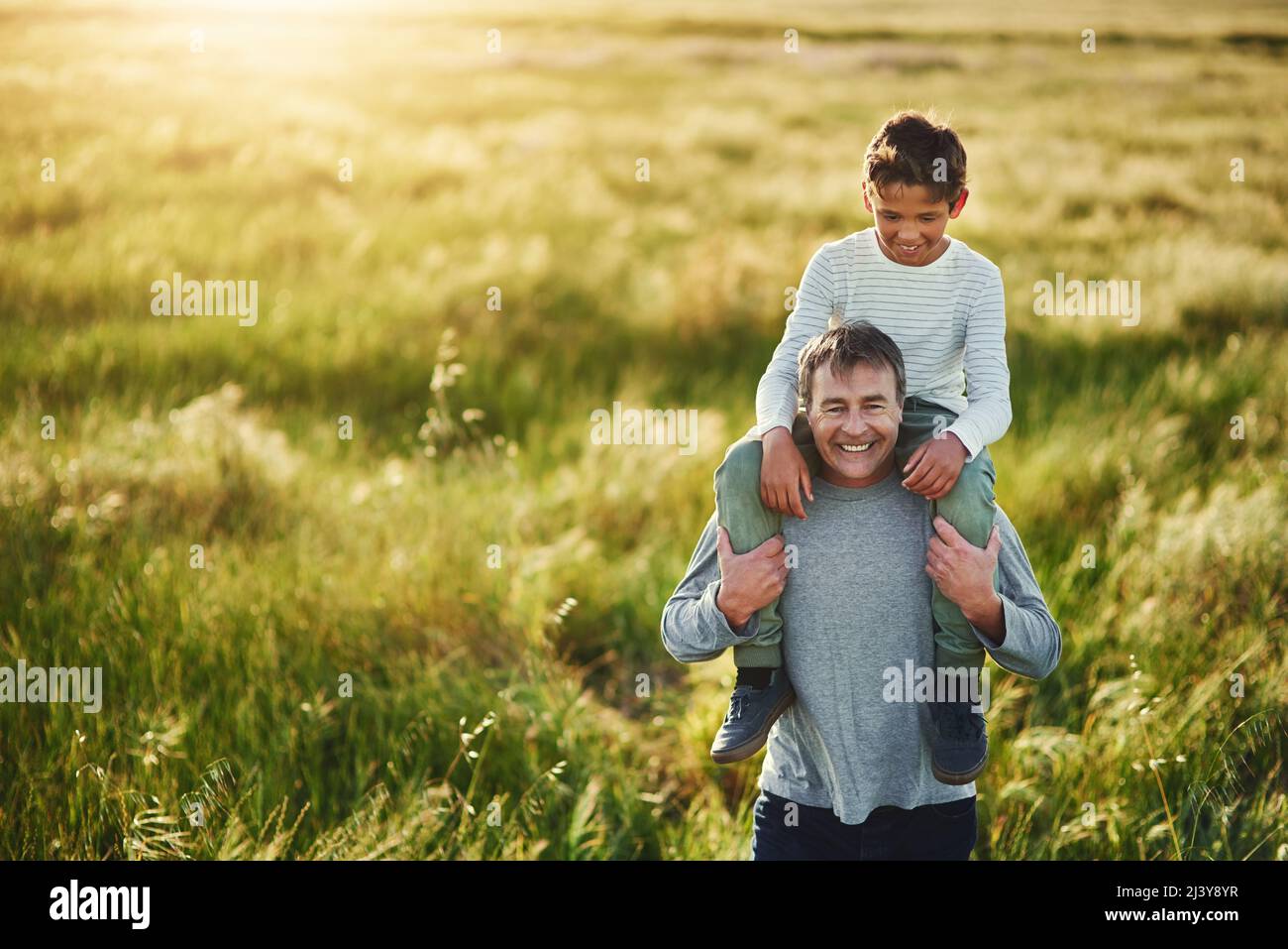 Setting off on an adventure together. Shot of a father carrying his son on his shoulders ...