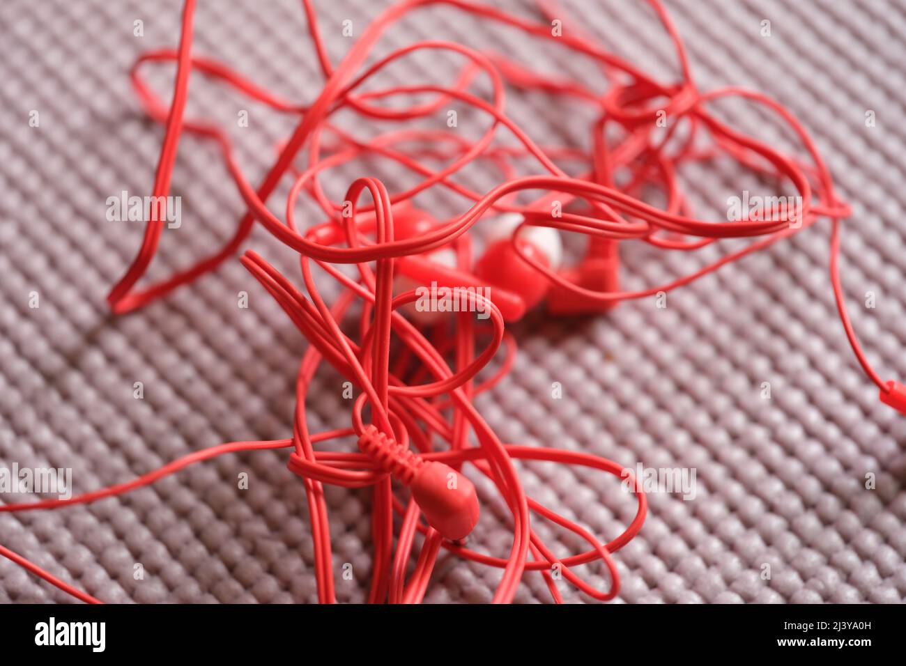 Tangled red wired headphones on gray background Stock Photo - Alamy