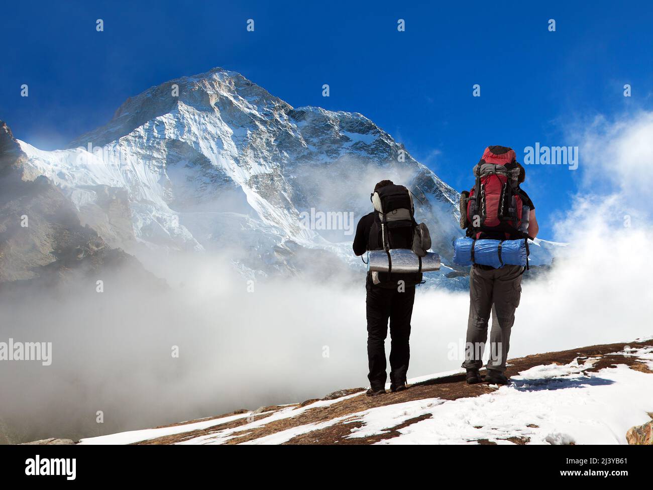Mount Makalu with clouds and silhouette of two hikers, Nepal Himalayas ...