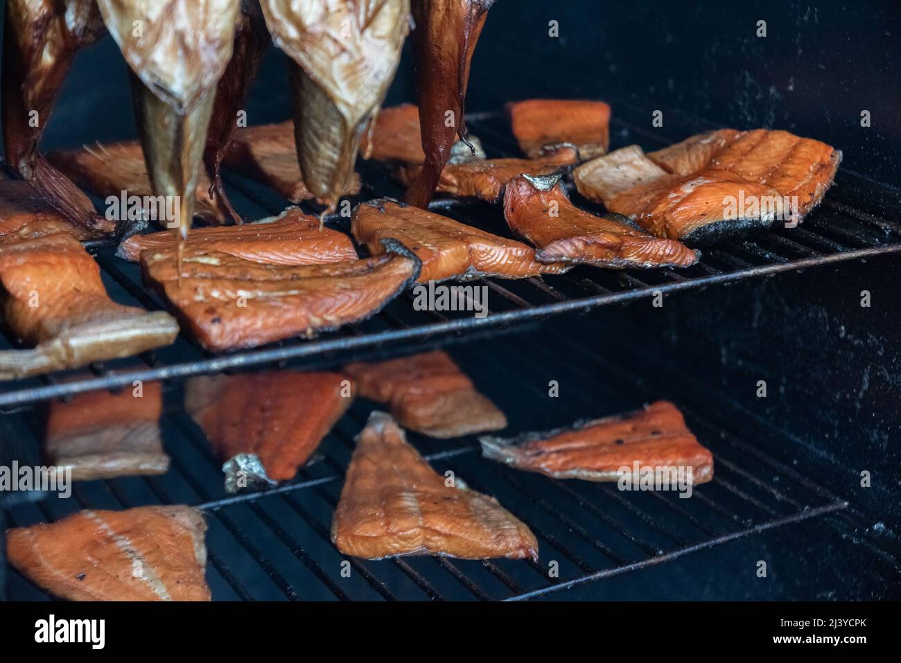 Freshly smoked fish hanging in smoke in a smokehouse. The tradition of ...