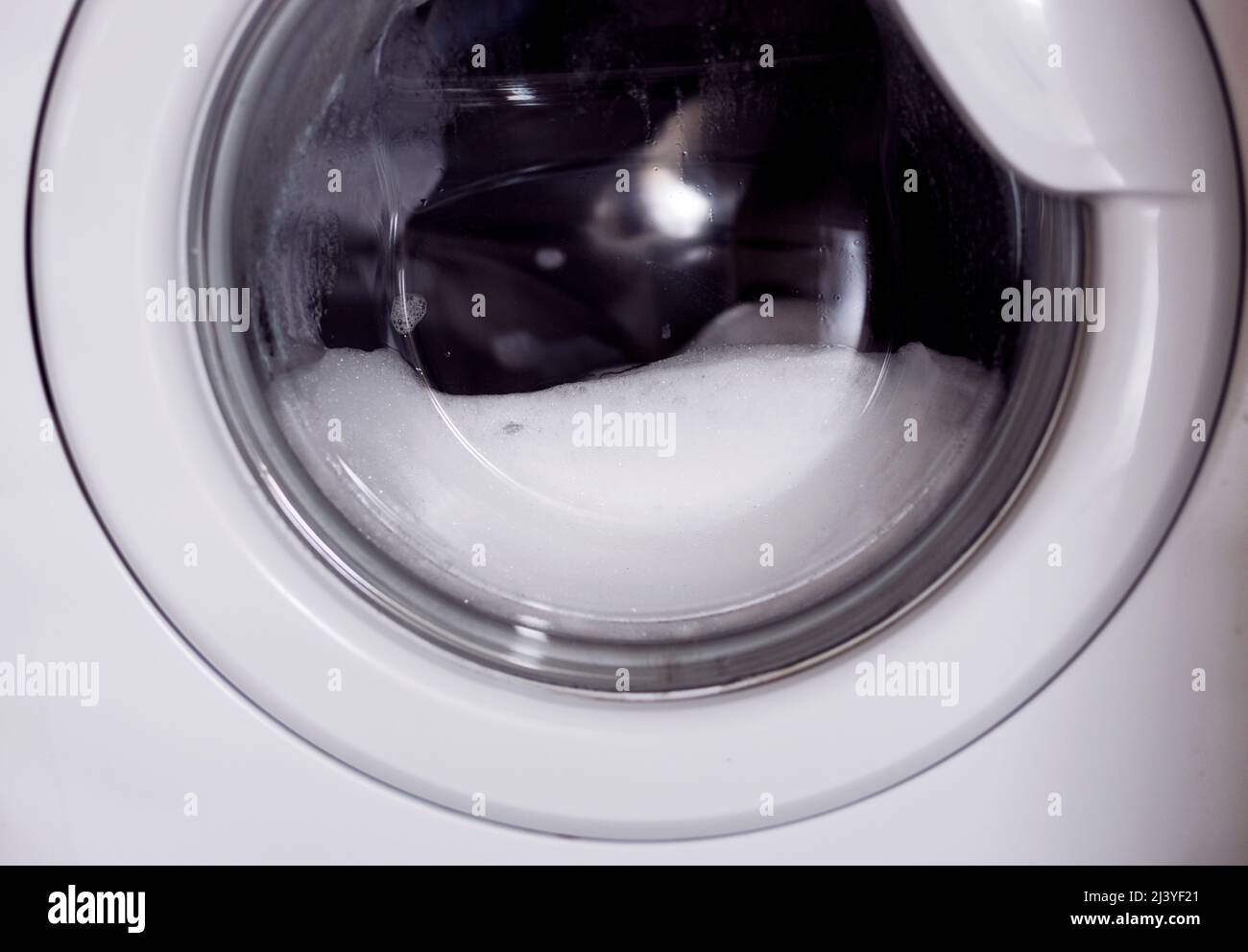 washing machine with dirty clothes inside make foam. water bubble ...