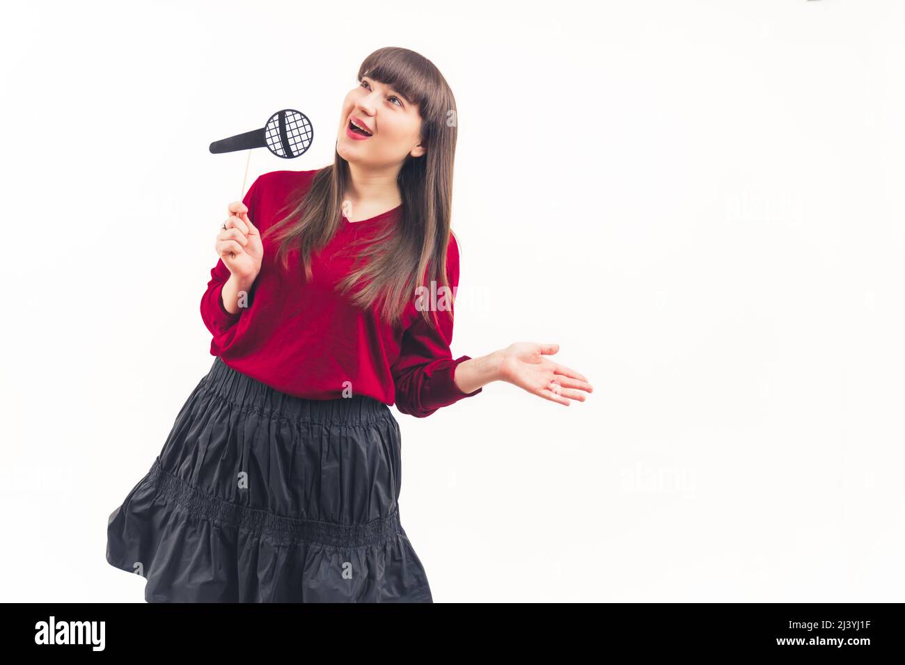 Beautiful young woman singing into a fake props microphone white ...