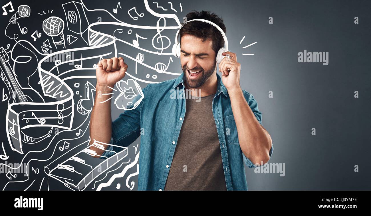 Jamming out to the music. Studio shot of a handsome young man listening ...