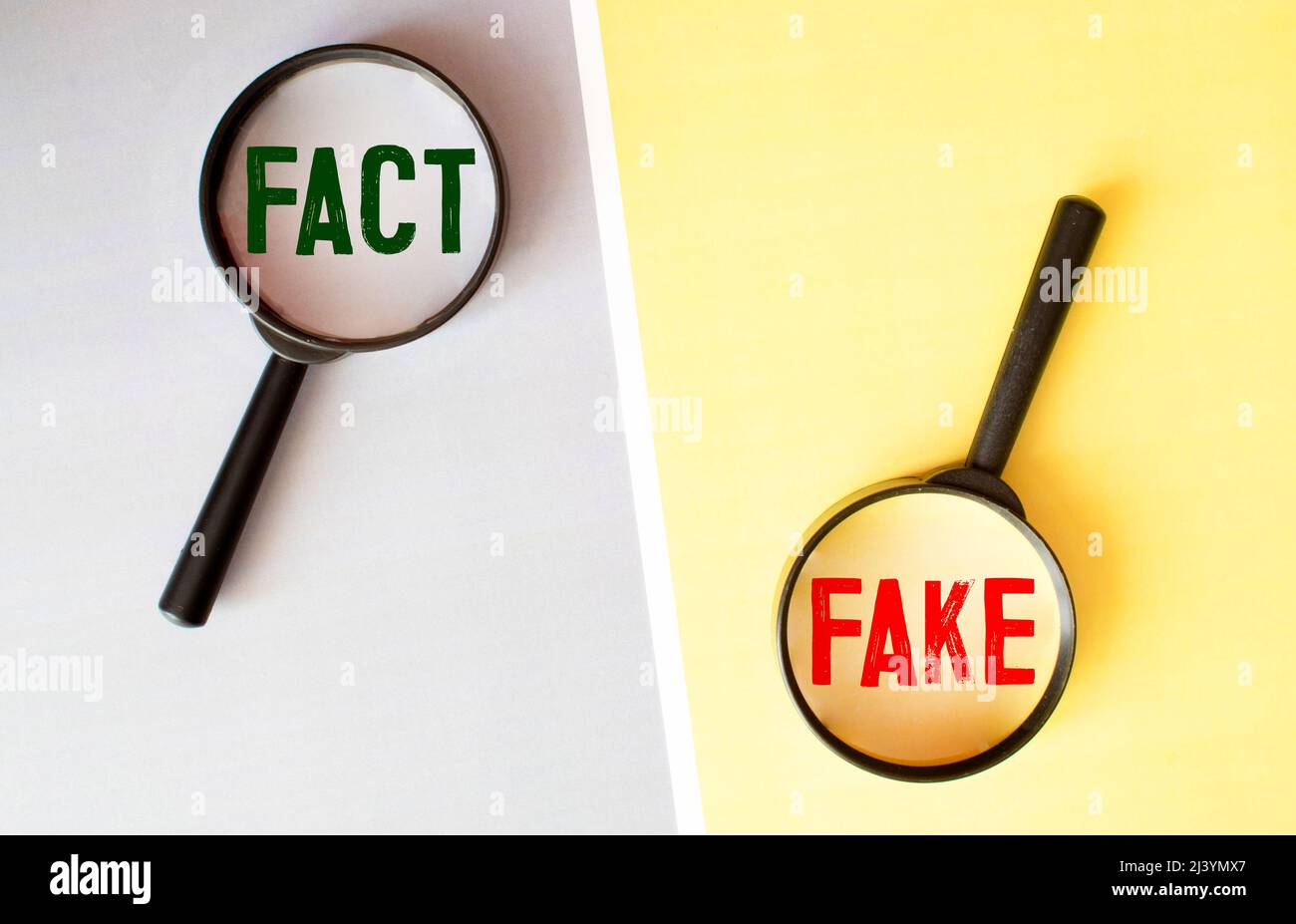 A magnifying glass looking to the words fact fake made with letter game ...