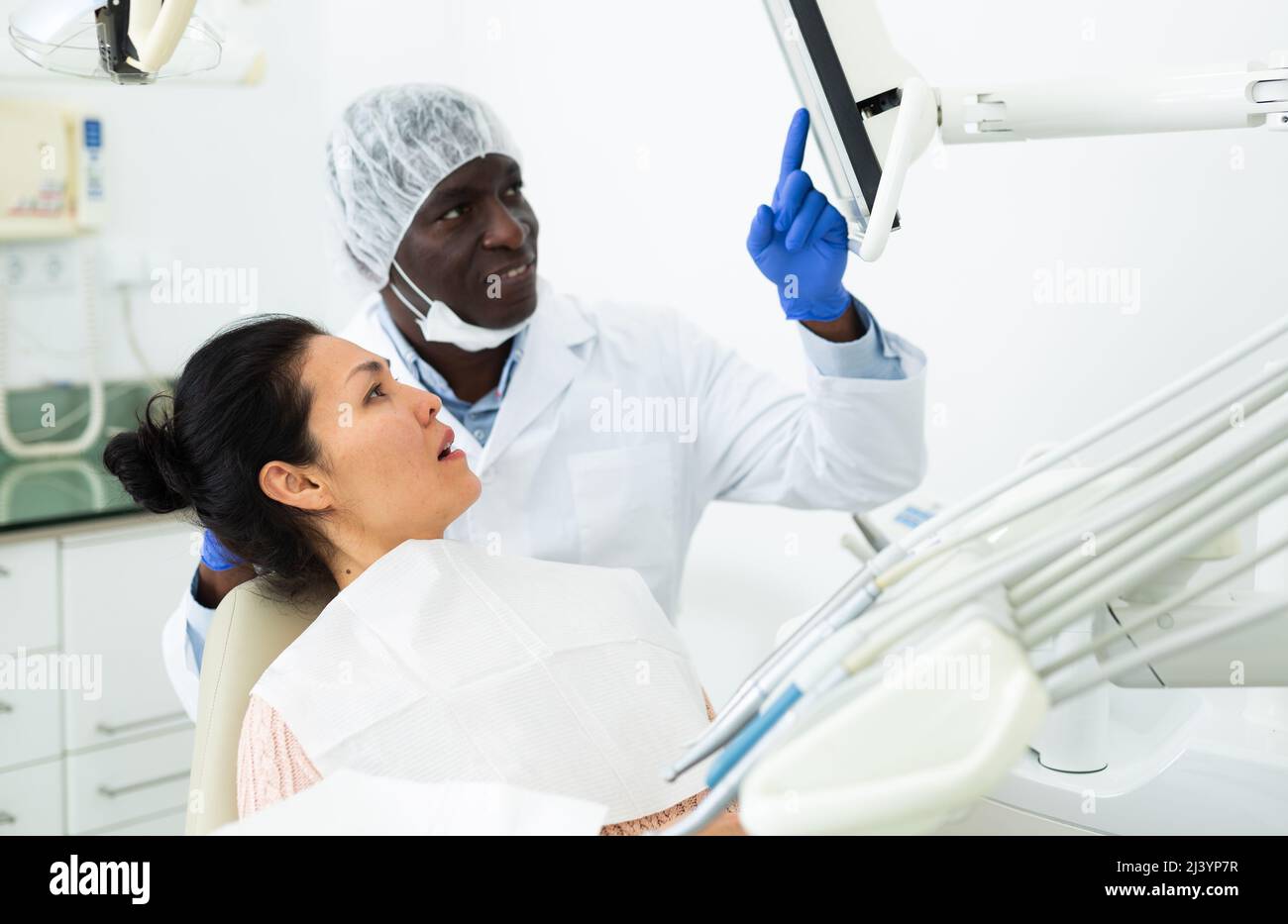 Doctor dentist showing woman patient x-ray of teeth on computer Stock ...