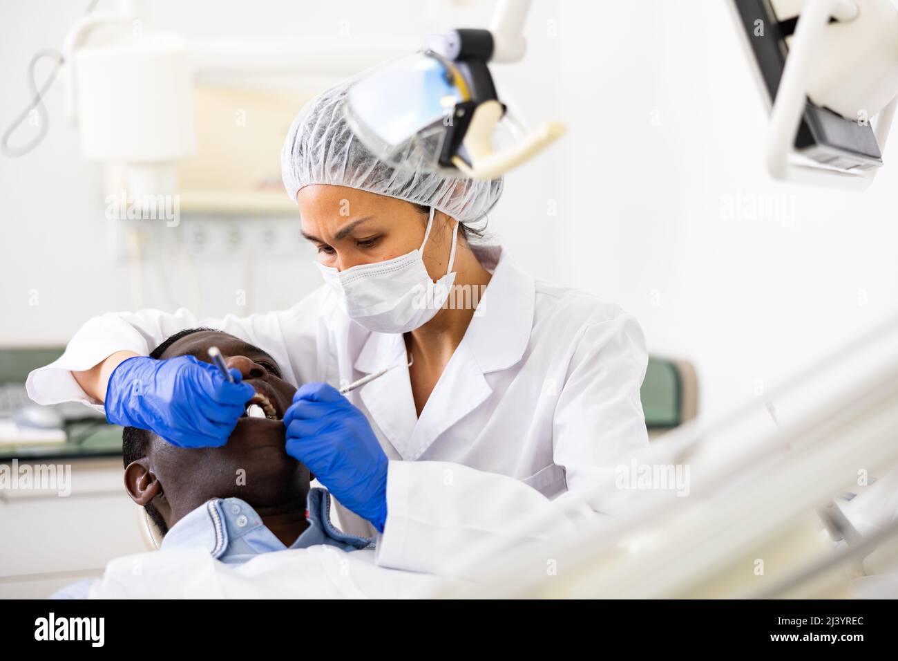 Orthodontist using tools and curing toothache of african-american man ...