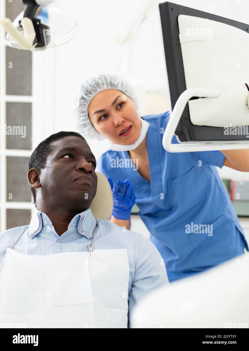 Female stomatologist showing teeth radiography result on computer to ...