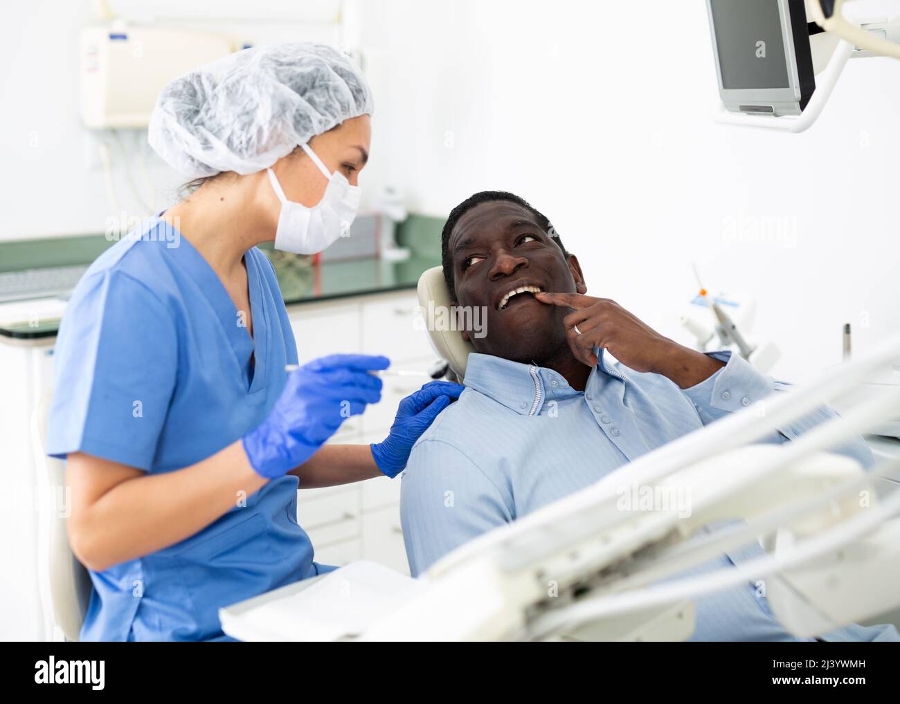 Patient pointing at tooth with problem during consultation in dental ...