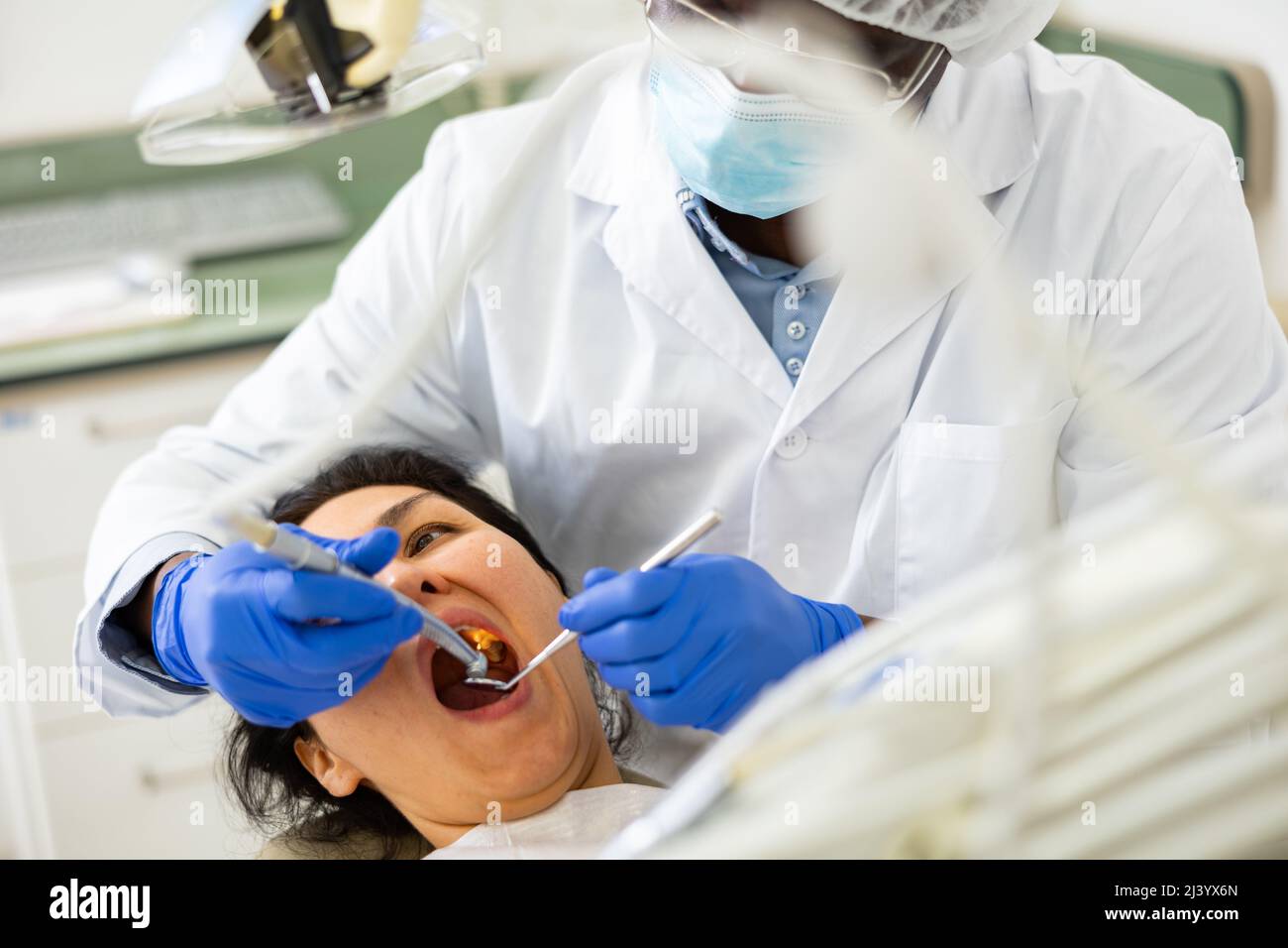 Dentist in face mask inspects female patient teeth with mirror Stock ...