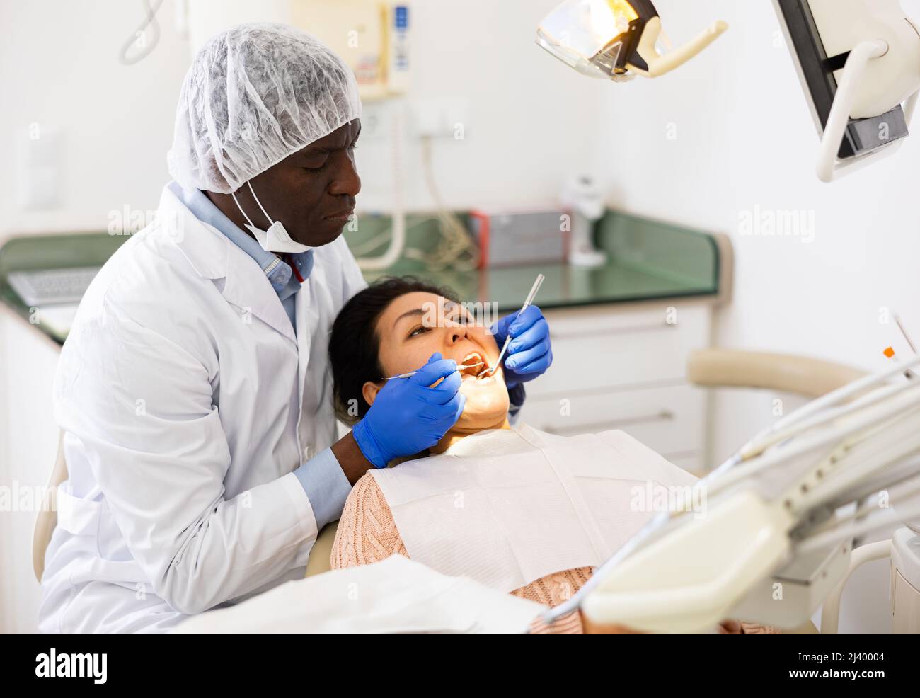 Professional dentist performing teeth treatment to woman at dental ...