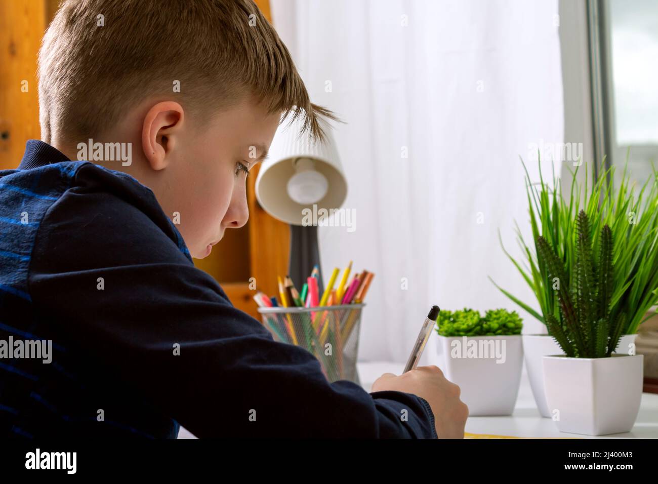 Teenager doing homework sitting at white desk Stock Photo - Alamy
