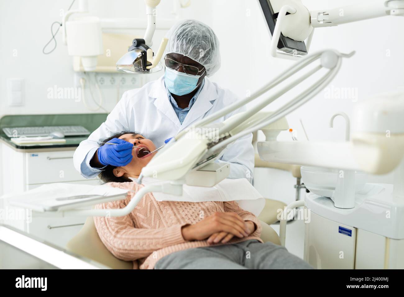 African american dentist professional filling teeth for woman patient ...