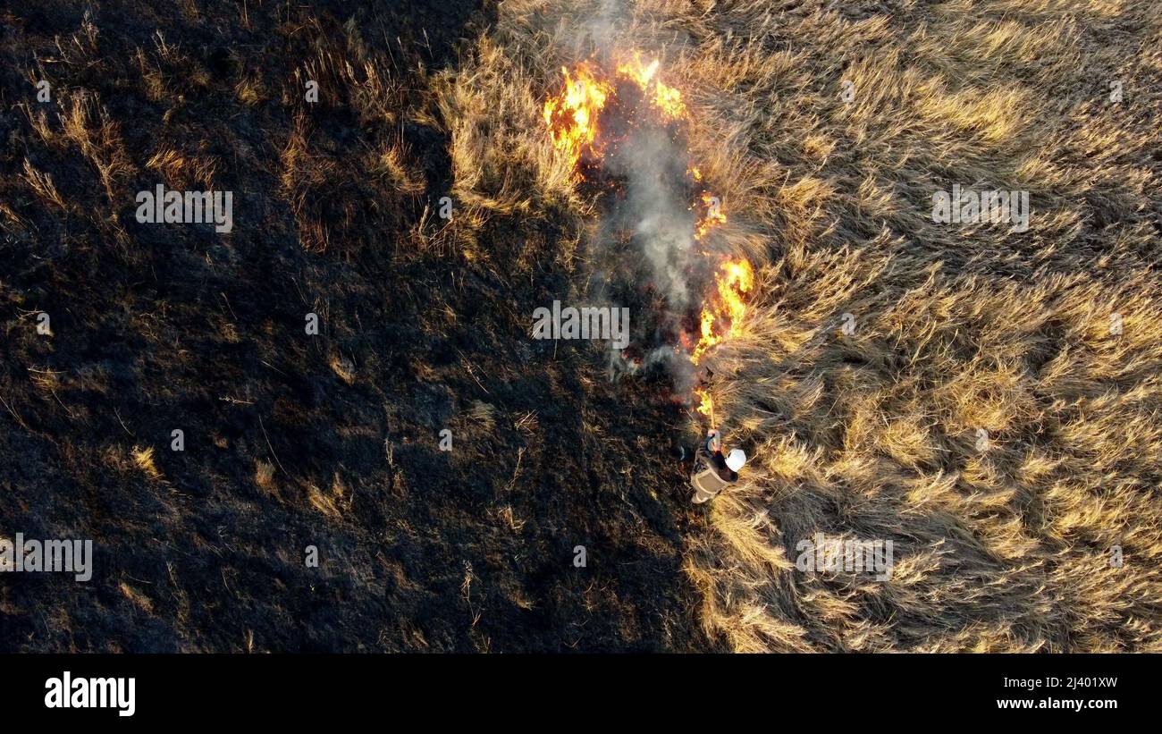 Aerial Fire extinguishing. Fireman extinguishing burning dry grass ...