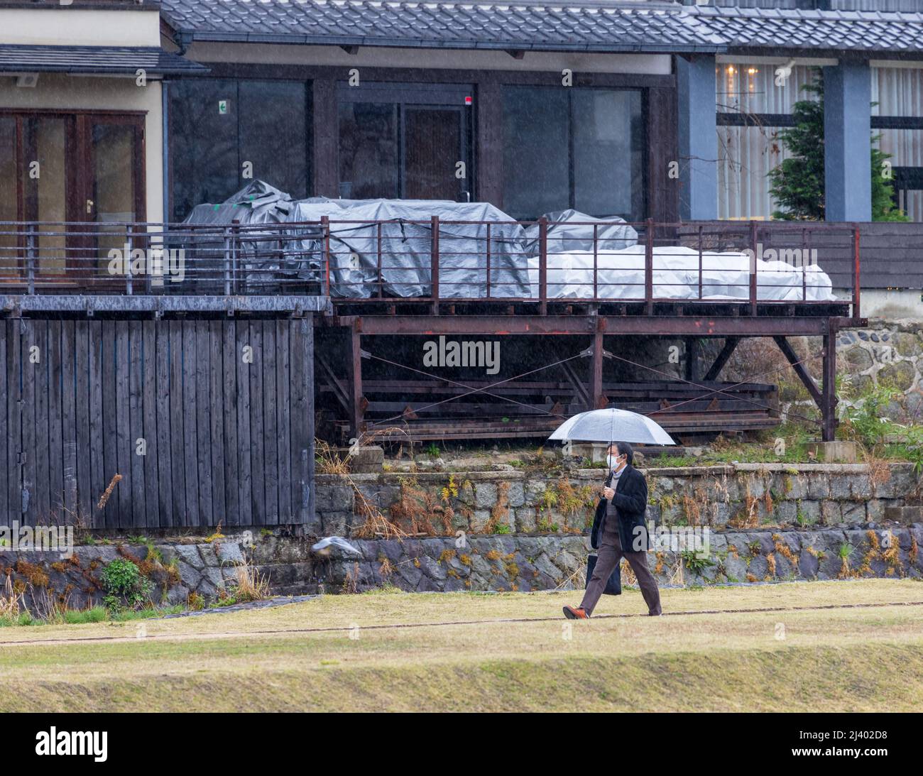 Lone masked businessman with clear umbrella walks in rain Stock Photo ...