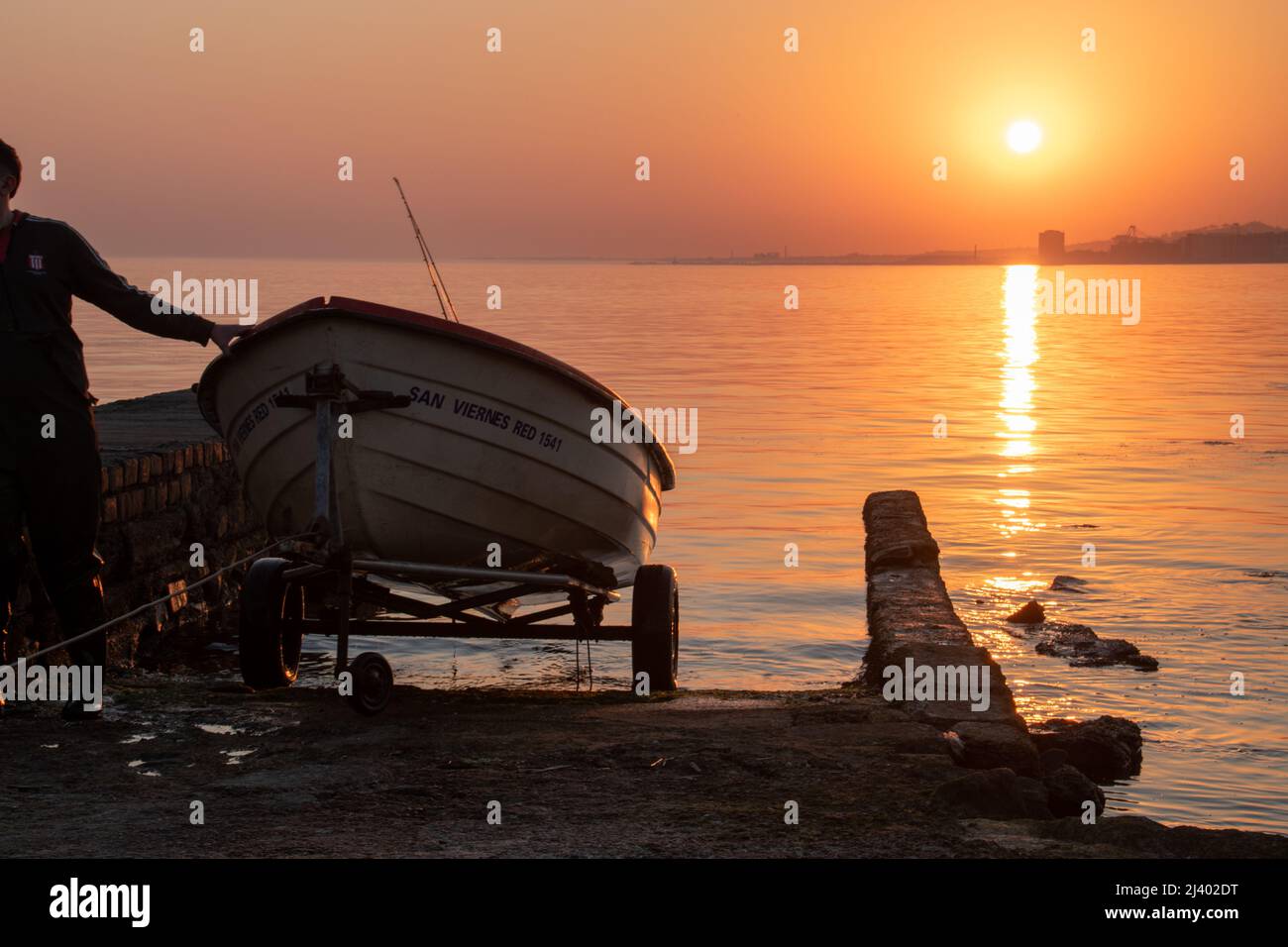 A man taking off a boat from the water during sunset Stock Photo - Alamy