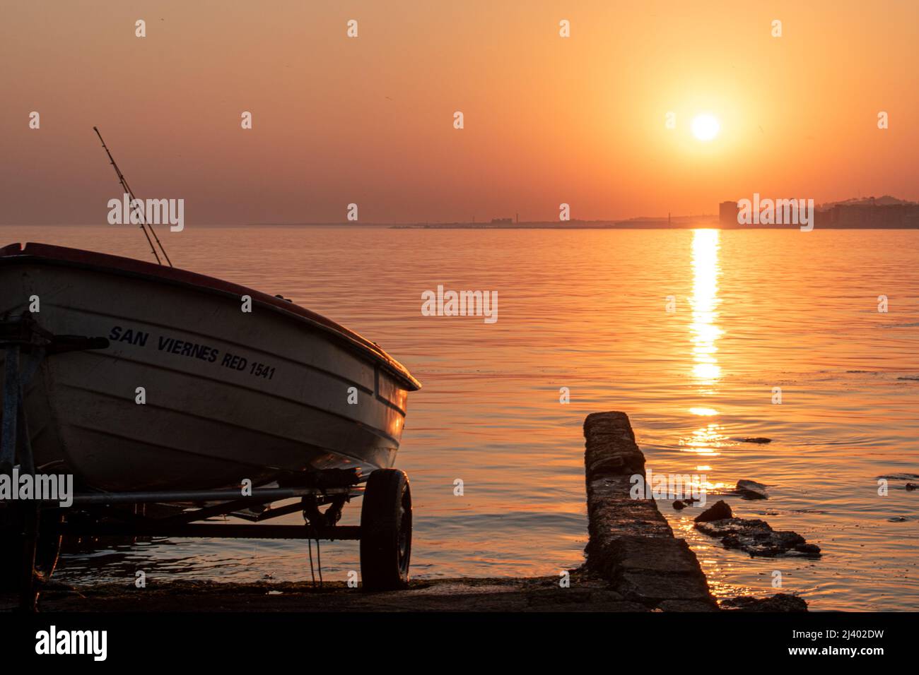 A man taking off a boat from the water during sunset Stock Photo - Alamy