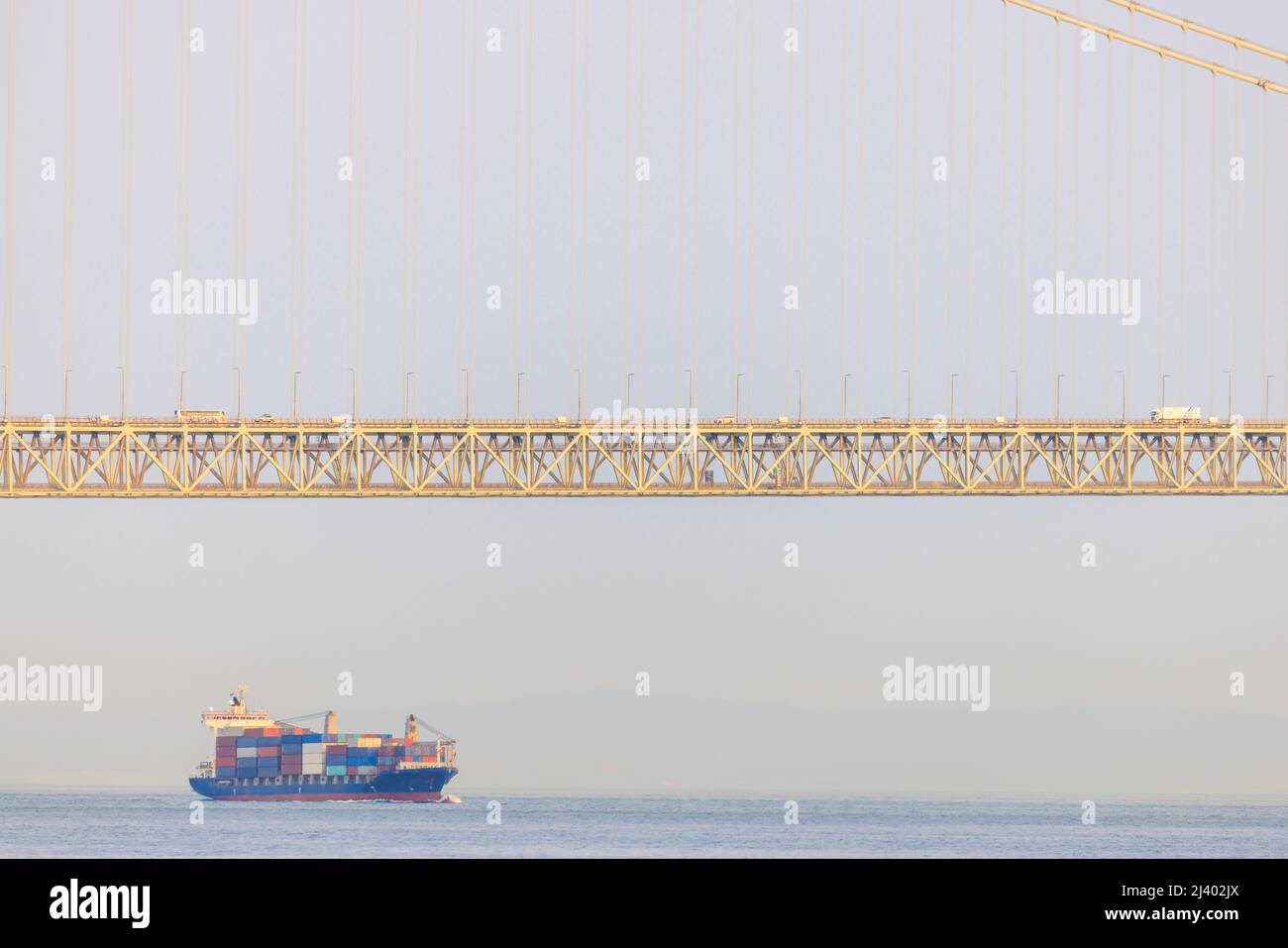 Cargo ship crossing under bridge span Stock Photo - Alamy
