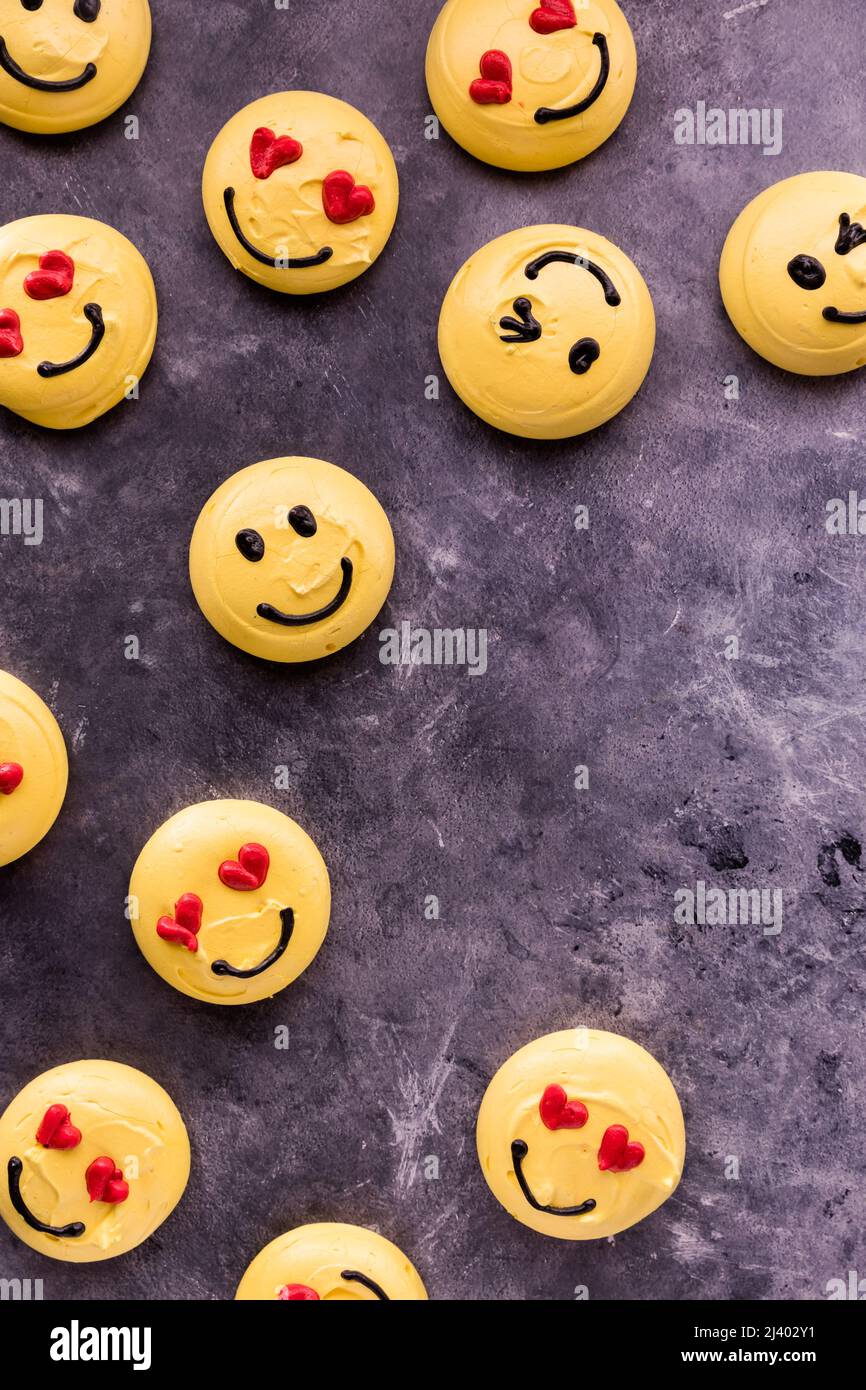 Several smiley face emoticon merengue cookies scattered around with ...