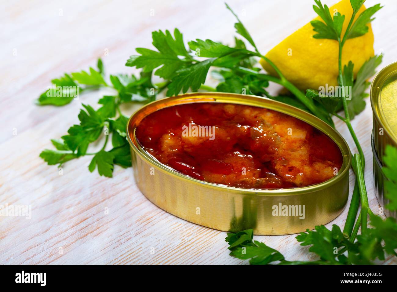 Tinned cod in tomato sauce on background with greens and lemon Stock ...