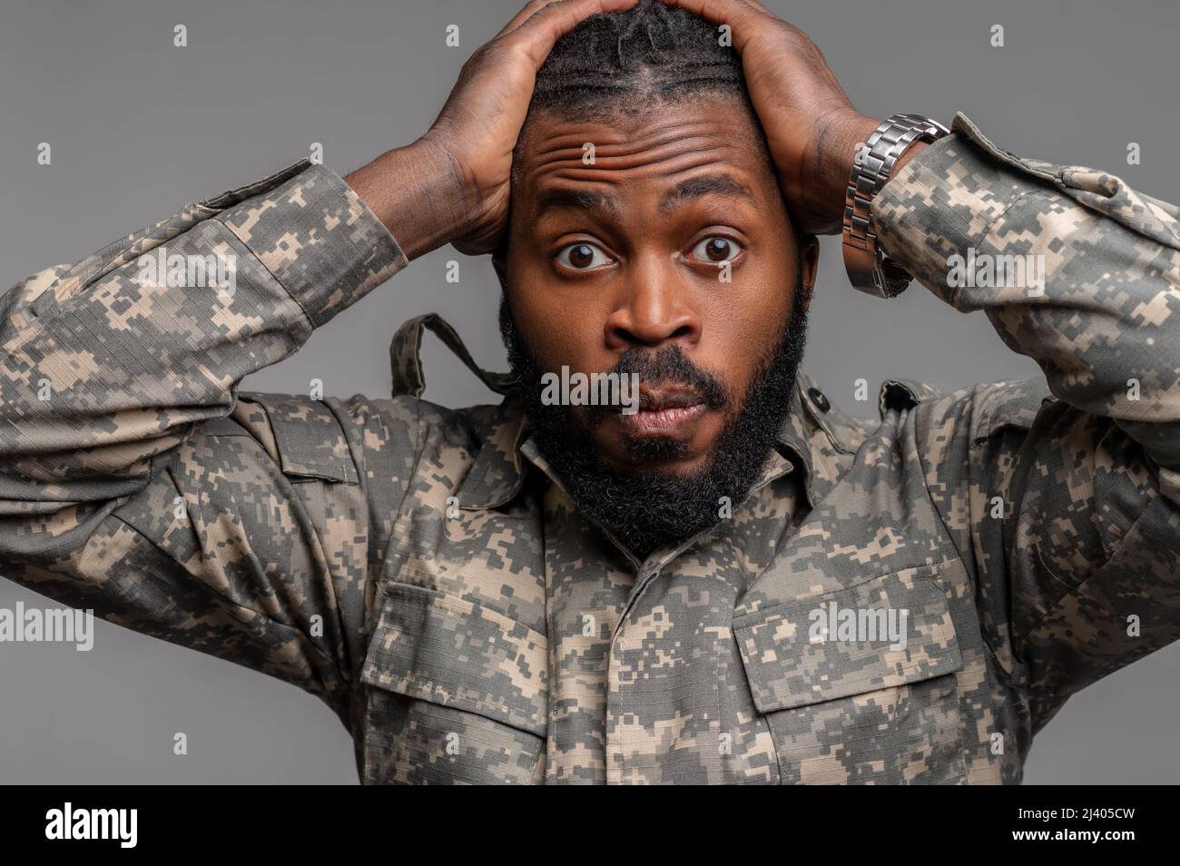 Portrait of a surprised young bearded mustached military man clutching ...