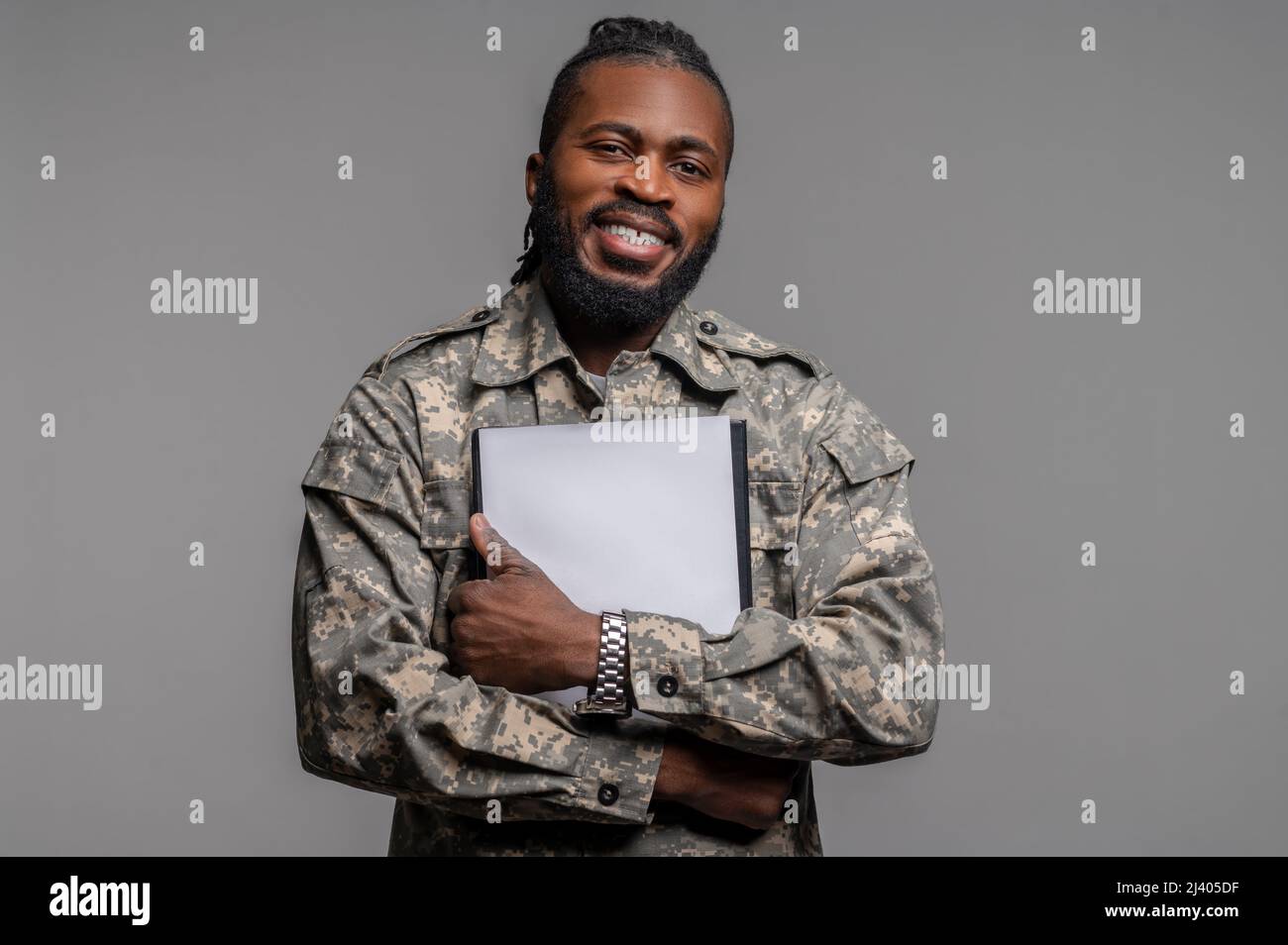 Waist-up portrait of a cheerful soldier holding the clipboard with a ...