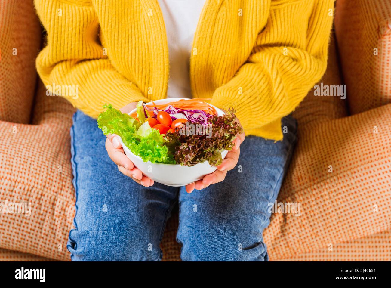 Female hands holding bowl with green lettuce salad on legs, Above front ...