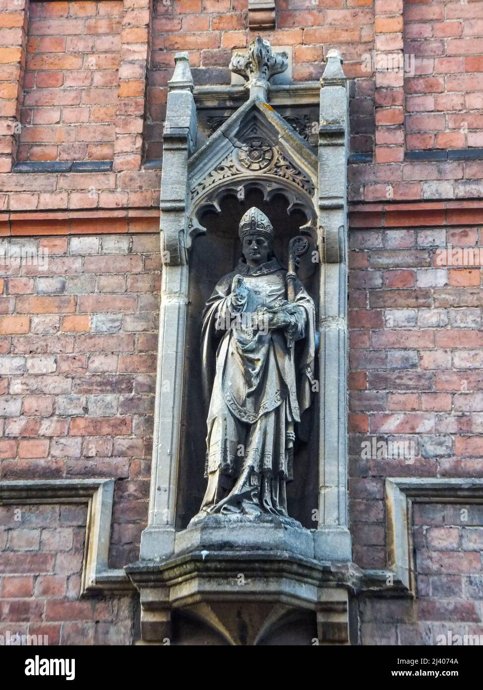 An old statue stands in an alcove on the wall of a building in Warwick ...
