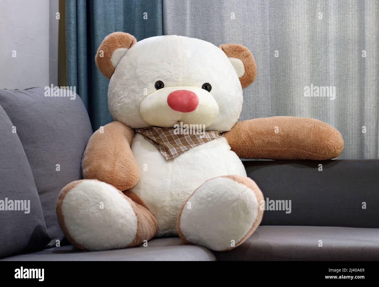 Big toy bear doll sitting and relaxing alone on big sofa Stock Photo ...