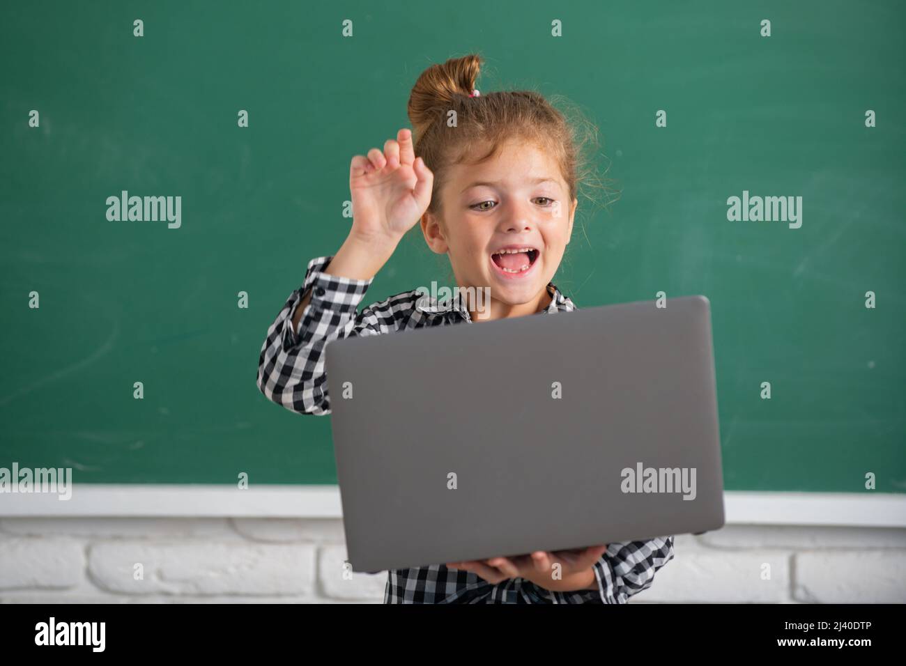 Excited student girl using laptop computer in school class on ...