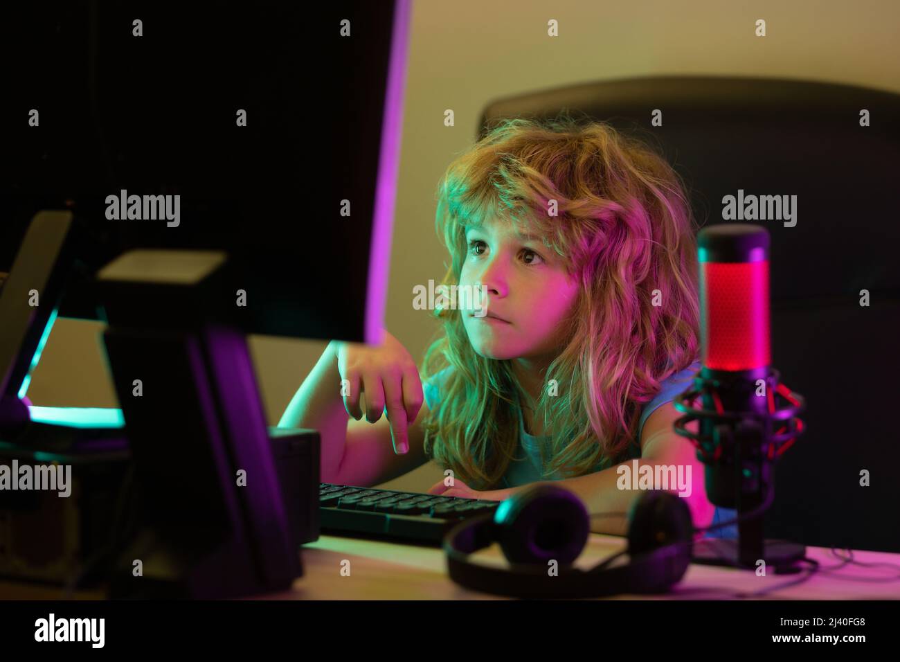 Child learning online at night, using desktop computer in living room ...