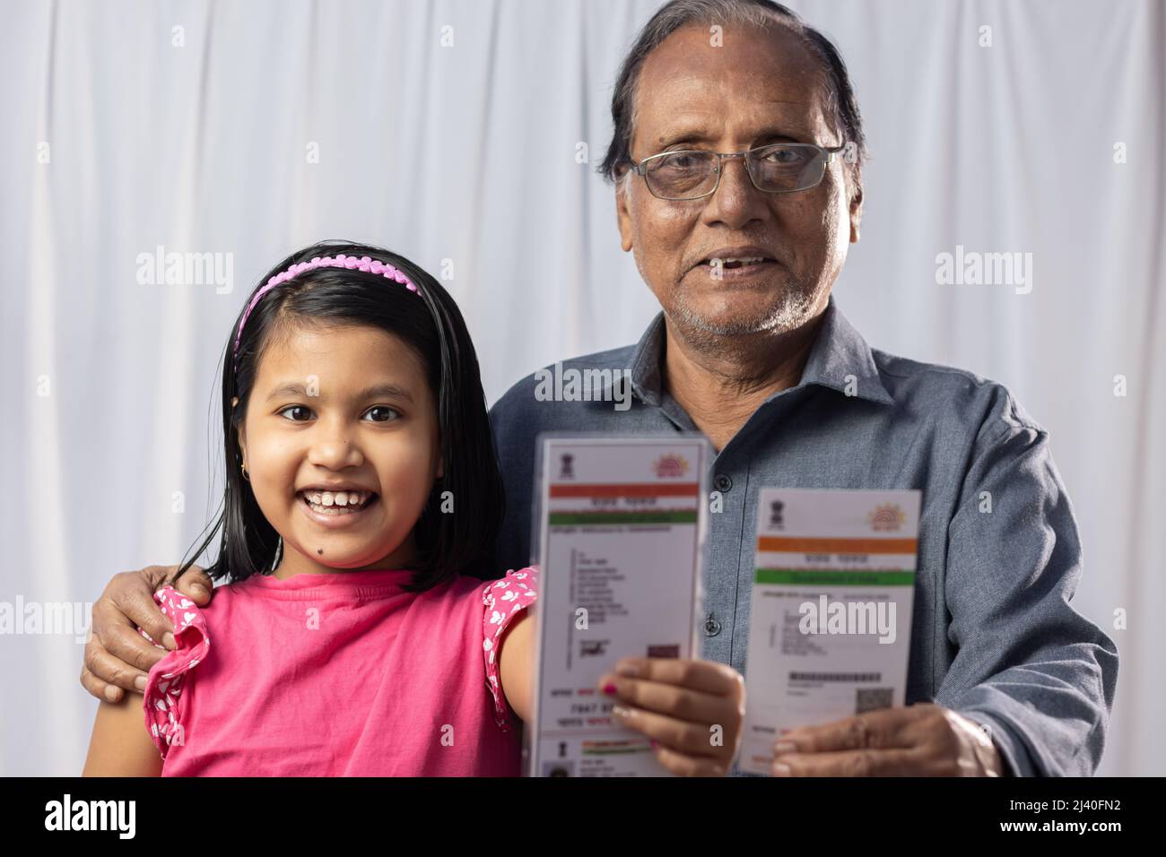 An Indian old man with his grand daughter smiling with Aadhaar card in ...