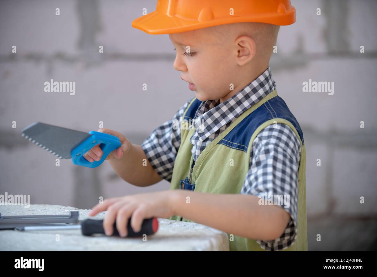 Preschool boy trying to saw, Child sawing on a construction site near ...
