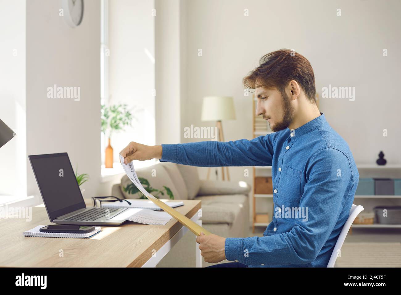 Serious young man reading business letter or some documents he got by ...
