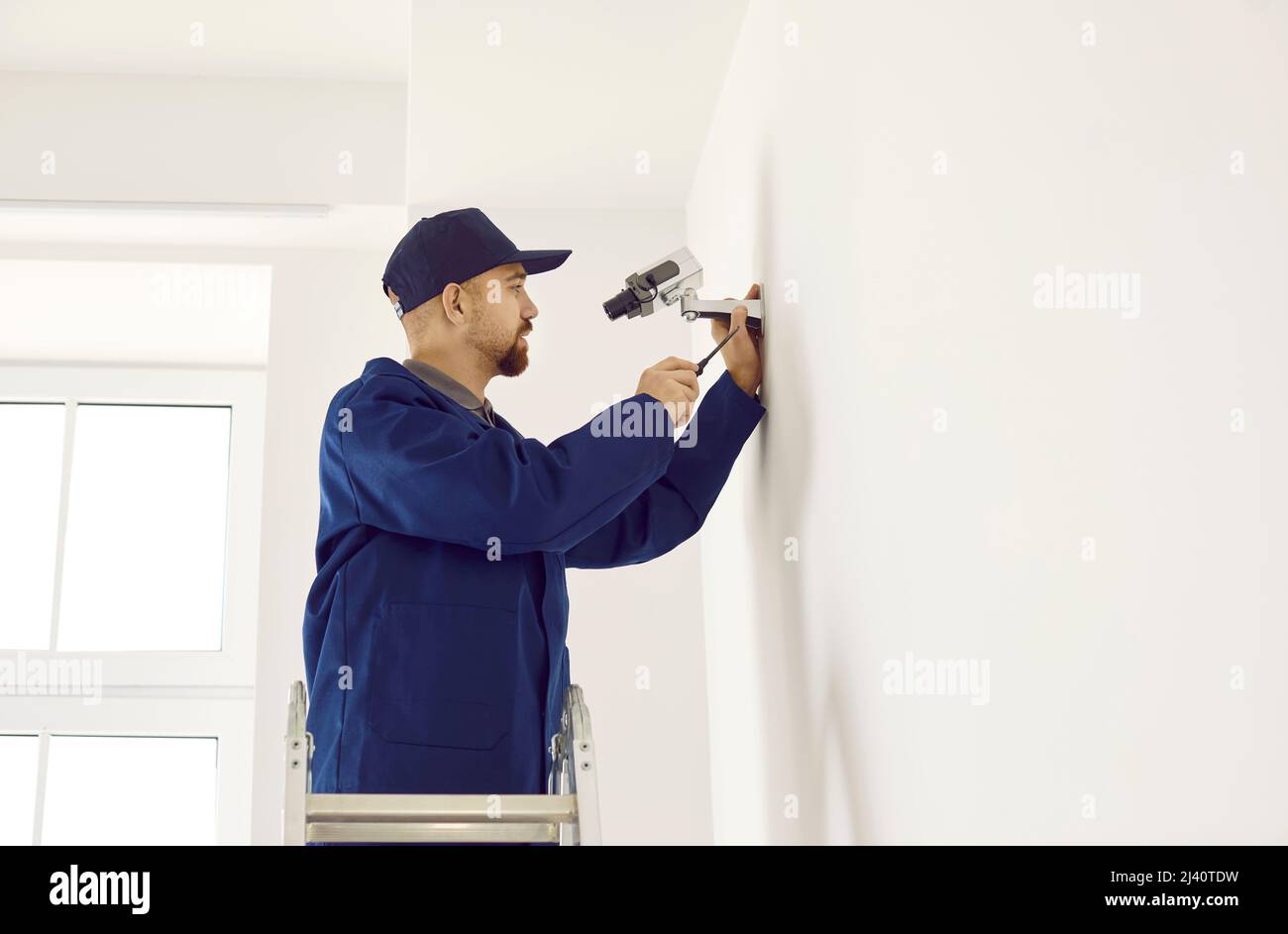 Male technician installing digital CCTV surveillance camera on wall ...