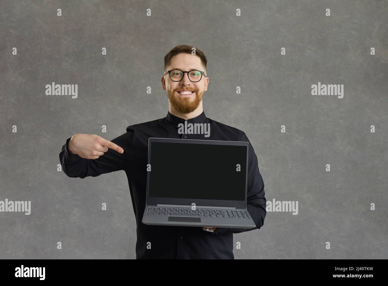 Studio portrait of happy young man pointing at blank screen of his ... Studio portrait of happy young man pointing at blank screen of his ...