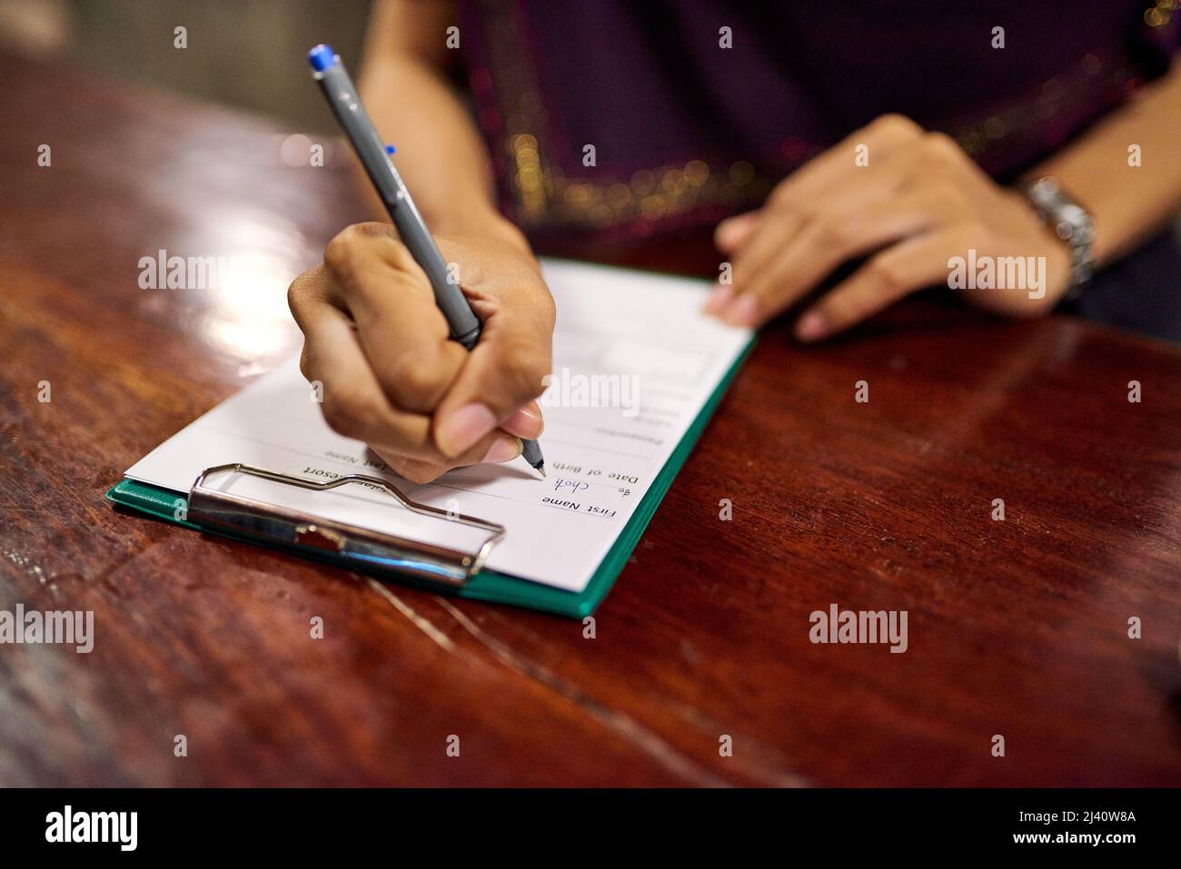 Time to check in. Closeup shot of a woman filling out a hotel check-in ...