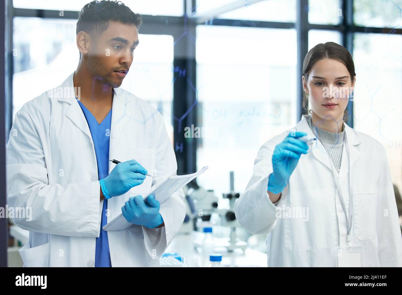 Doing the maths to prove their theory. Shot of two scientists solving ...