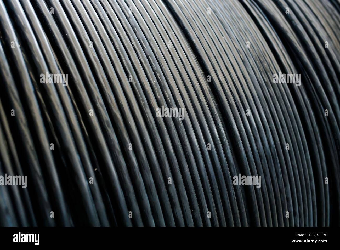 New black power cable is wound on wooden coil. Background. Cable for ...