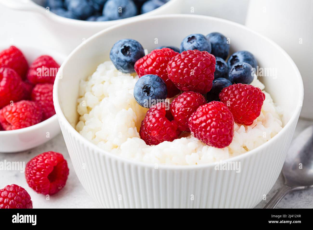 Rice pudding with berries and butter, close-up. Porridge bowl with ...