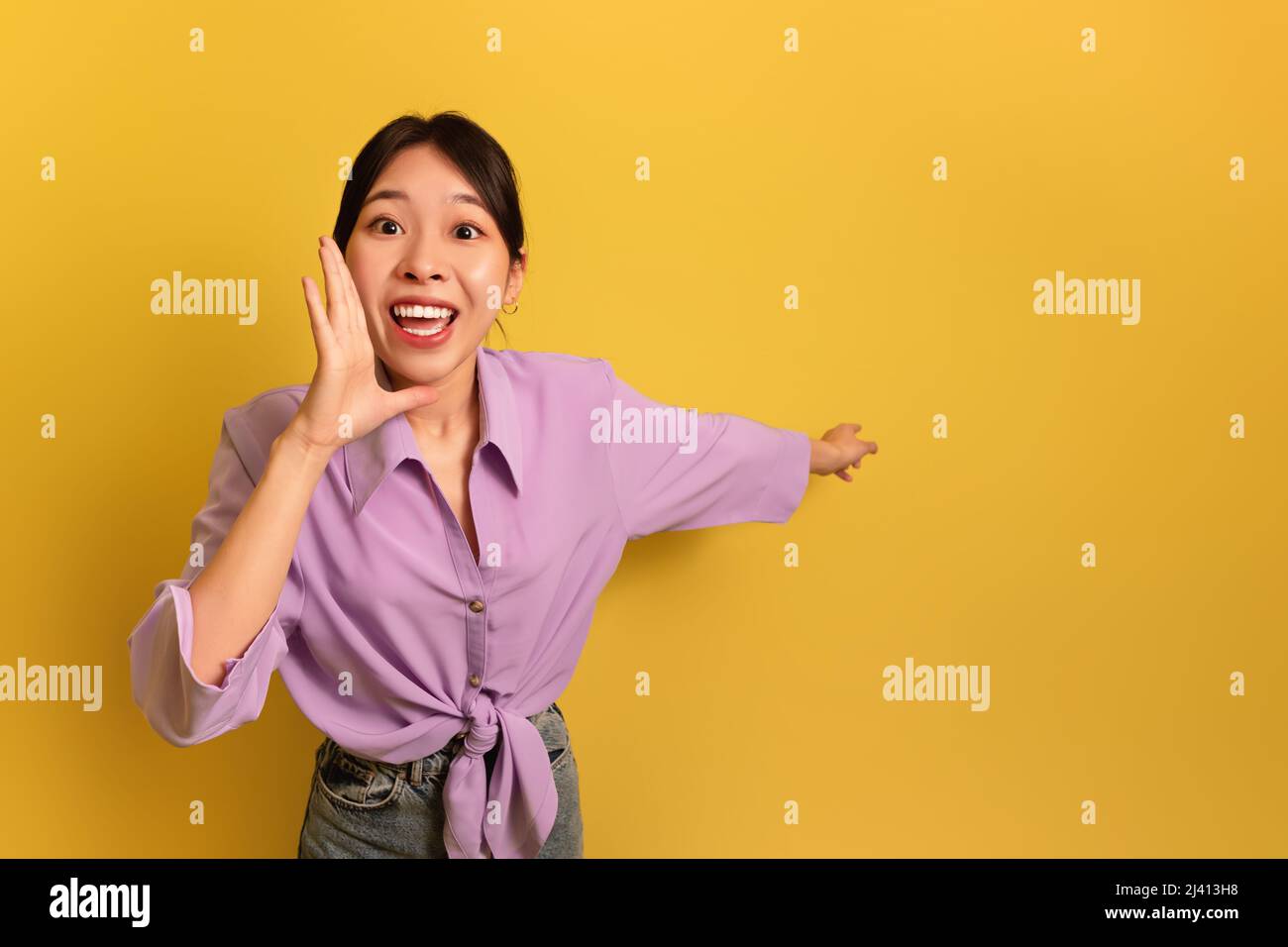 Excited young Asian woman shouting OMG and pointing at blank space on ...